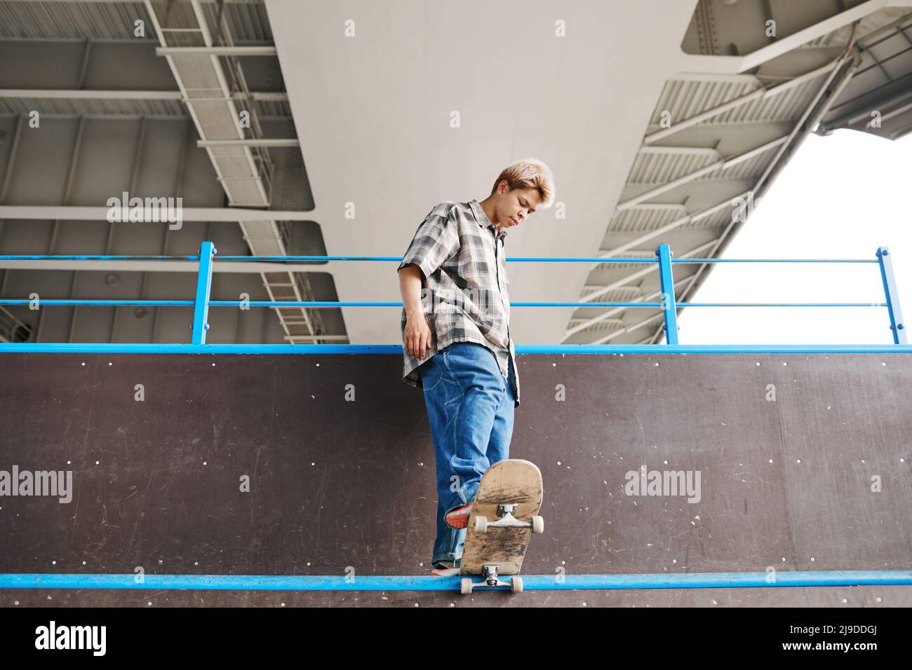 Full length portrait of teenage skater standing on ramp at skatepark ...