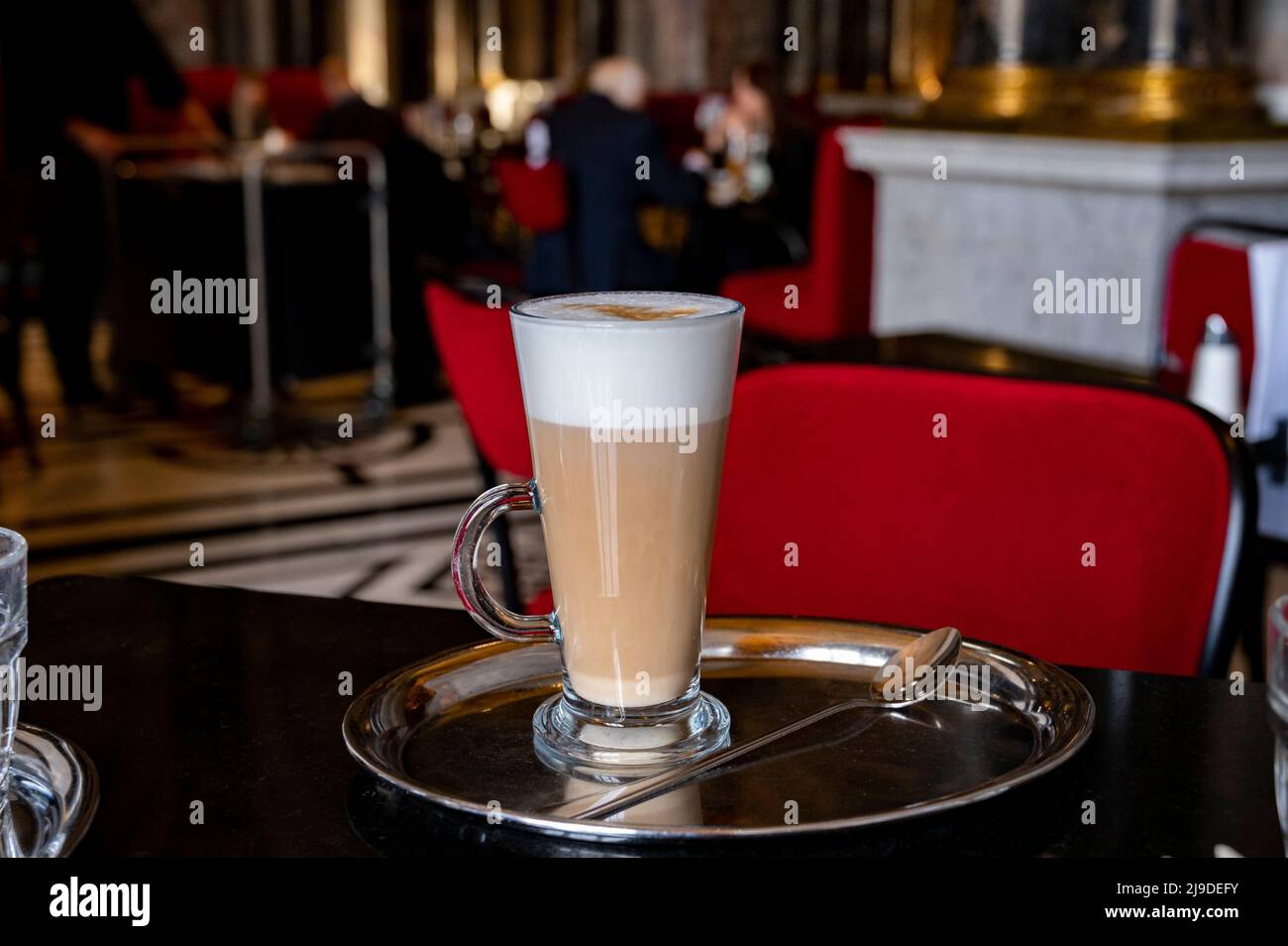 Glass cup of coffee latte served in classic old Austrian café ...