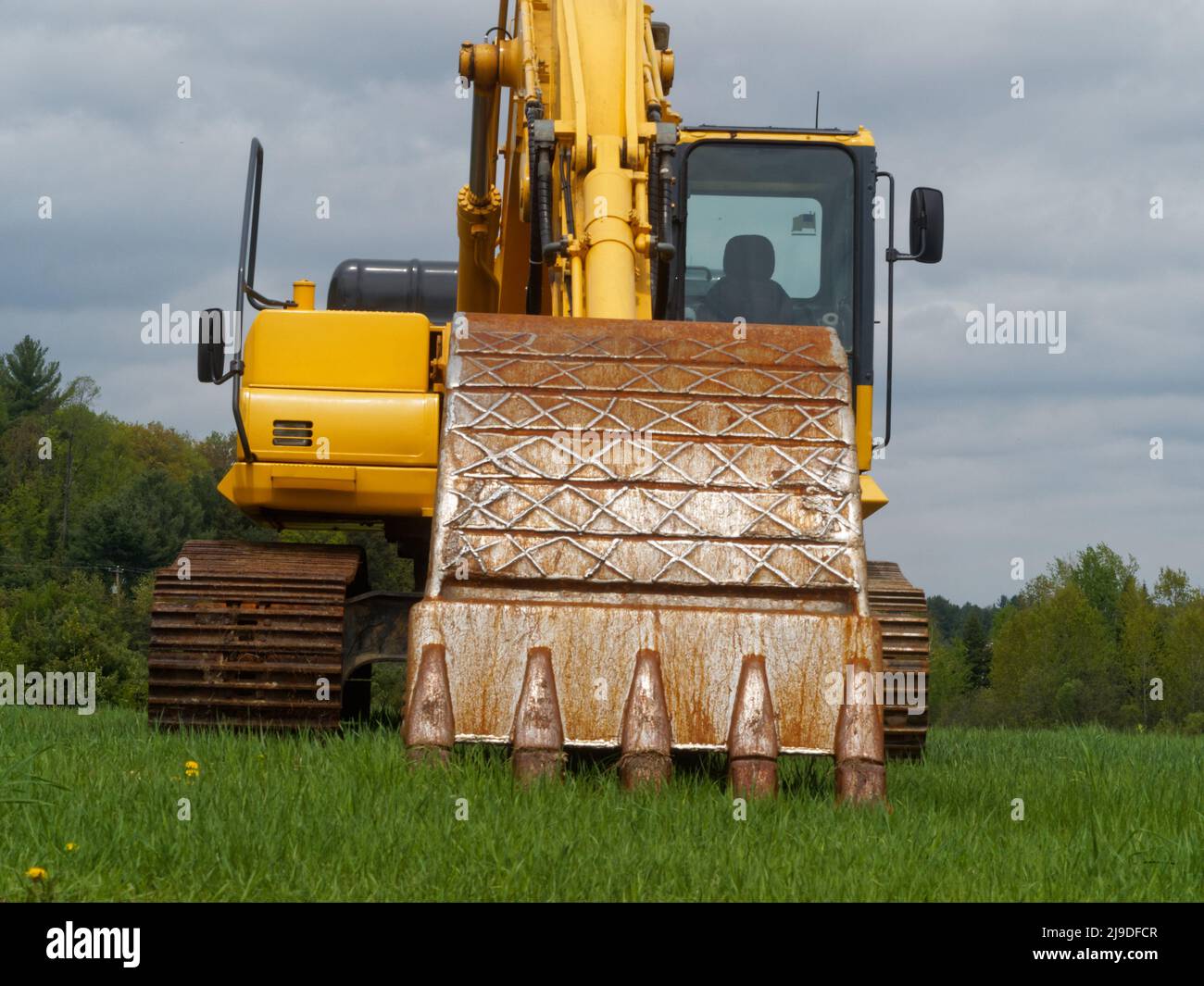 Excavator parked on grass Stock Photo - Alamy