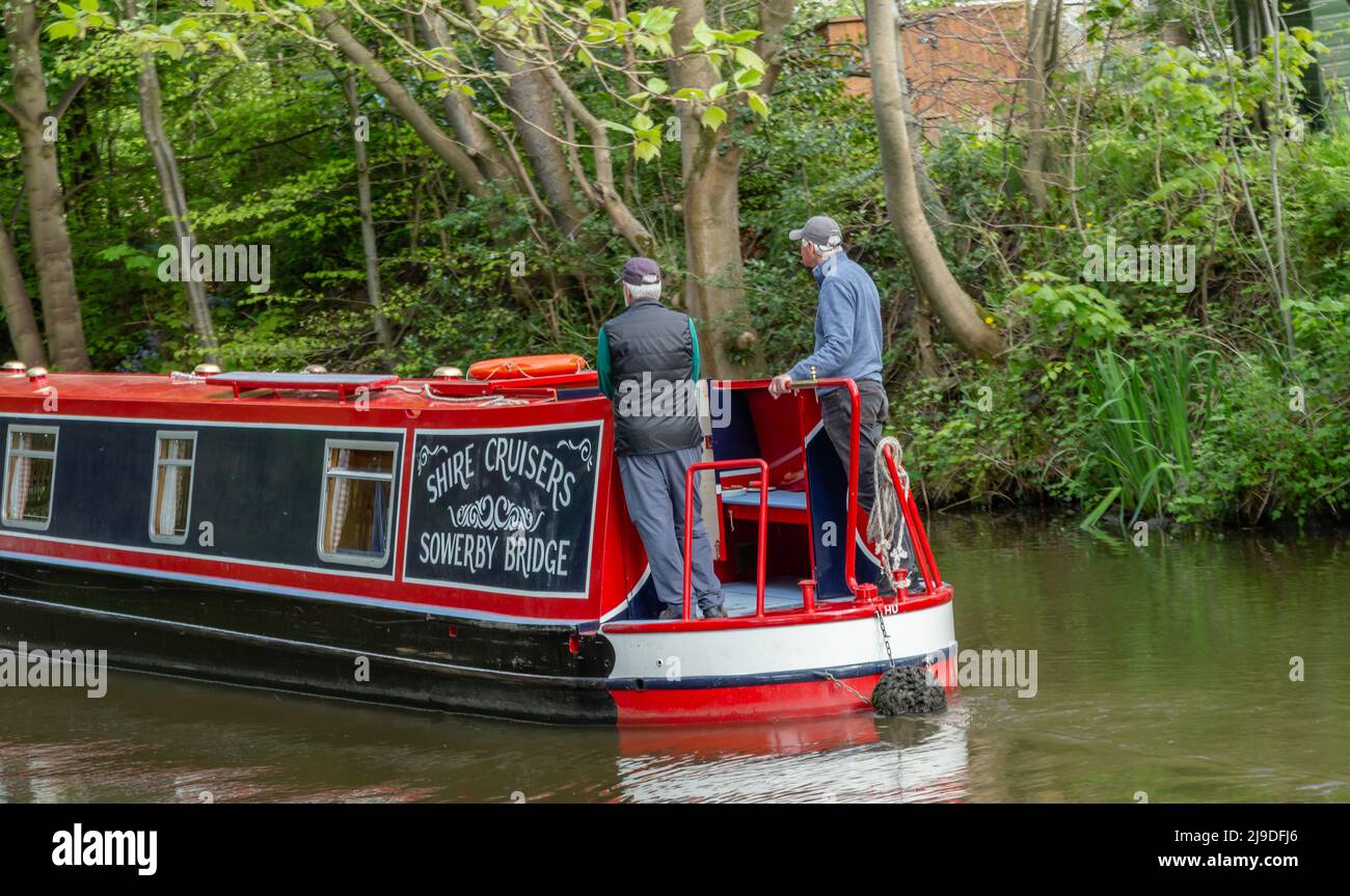 Two men travel along the Leeds Liverpool Canal on a barge at Saltaire ...