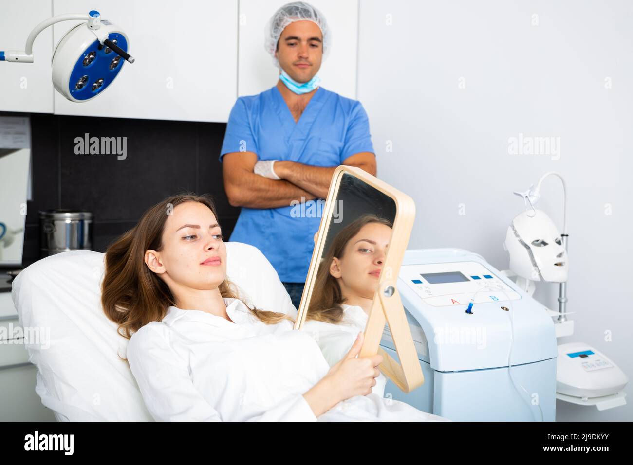 Woman patient looking in mirror after cosmetology procedure Stock Photo ...