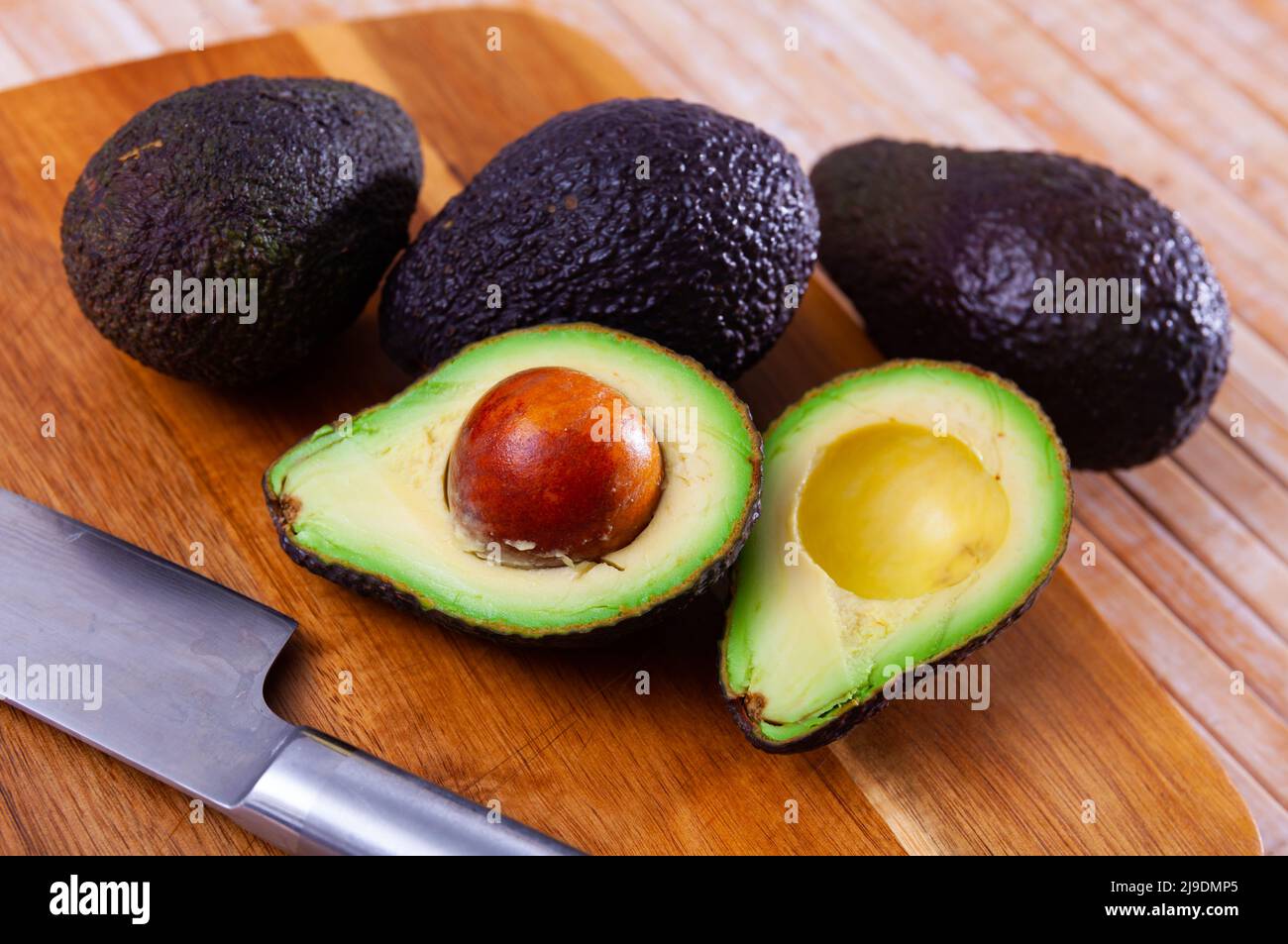 Whole and cut in half avocados on wooden background Stock Photo - Alamy
