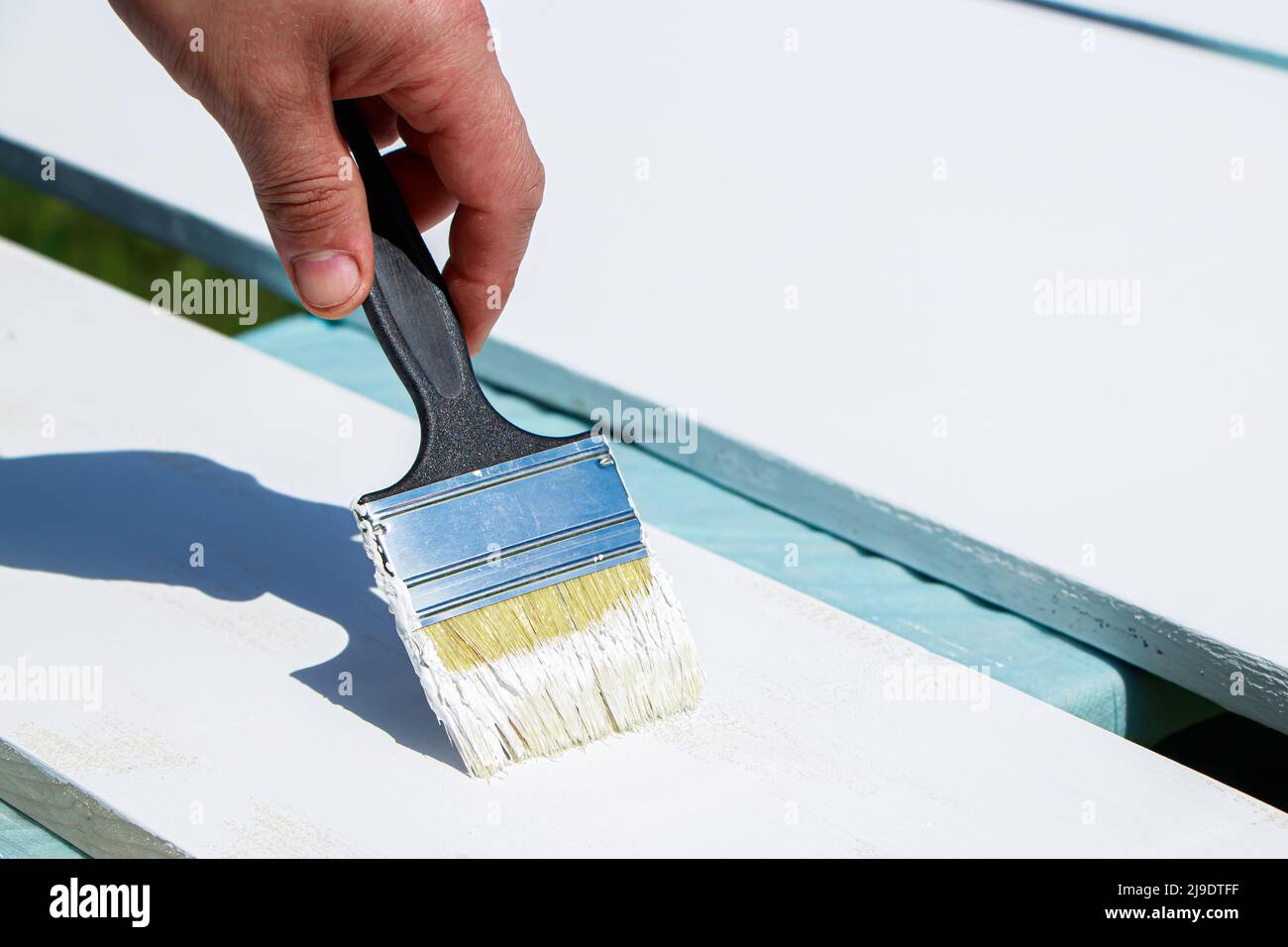 Male builder paints white boards for construction. Male hand holds ...