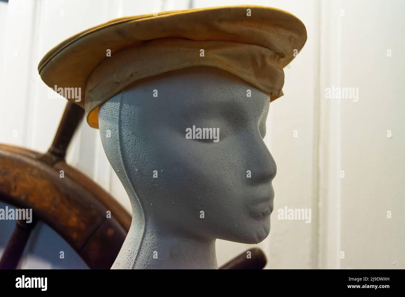 A foam manikin wearing a vintage sailors hat with a ships wheeel in the ...