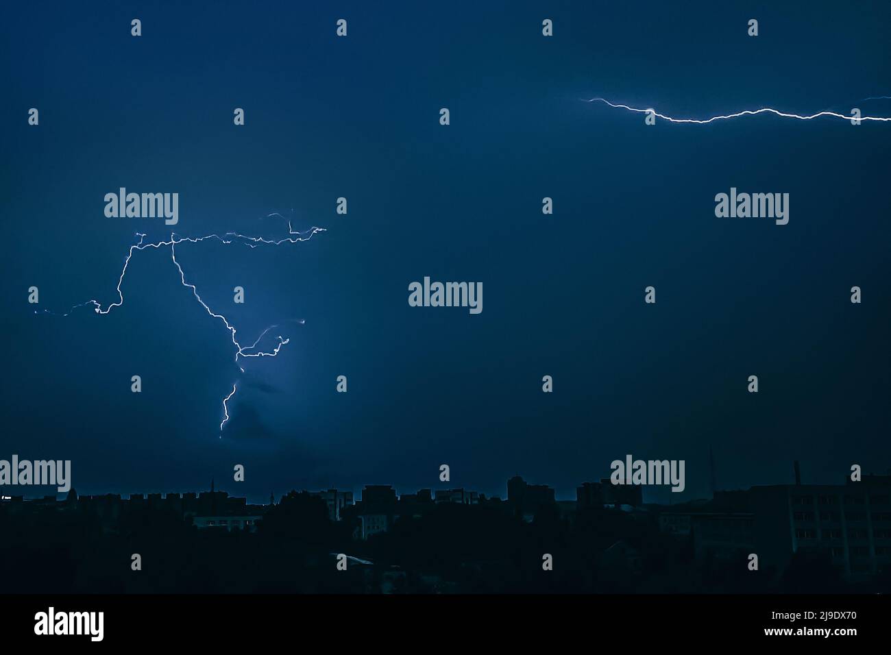 Lightning in sky over city. Bright flashes on dark night. Thunderclouds ...