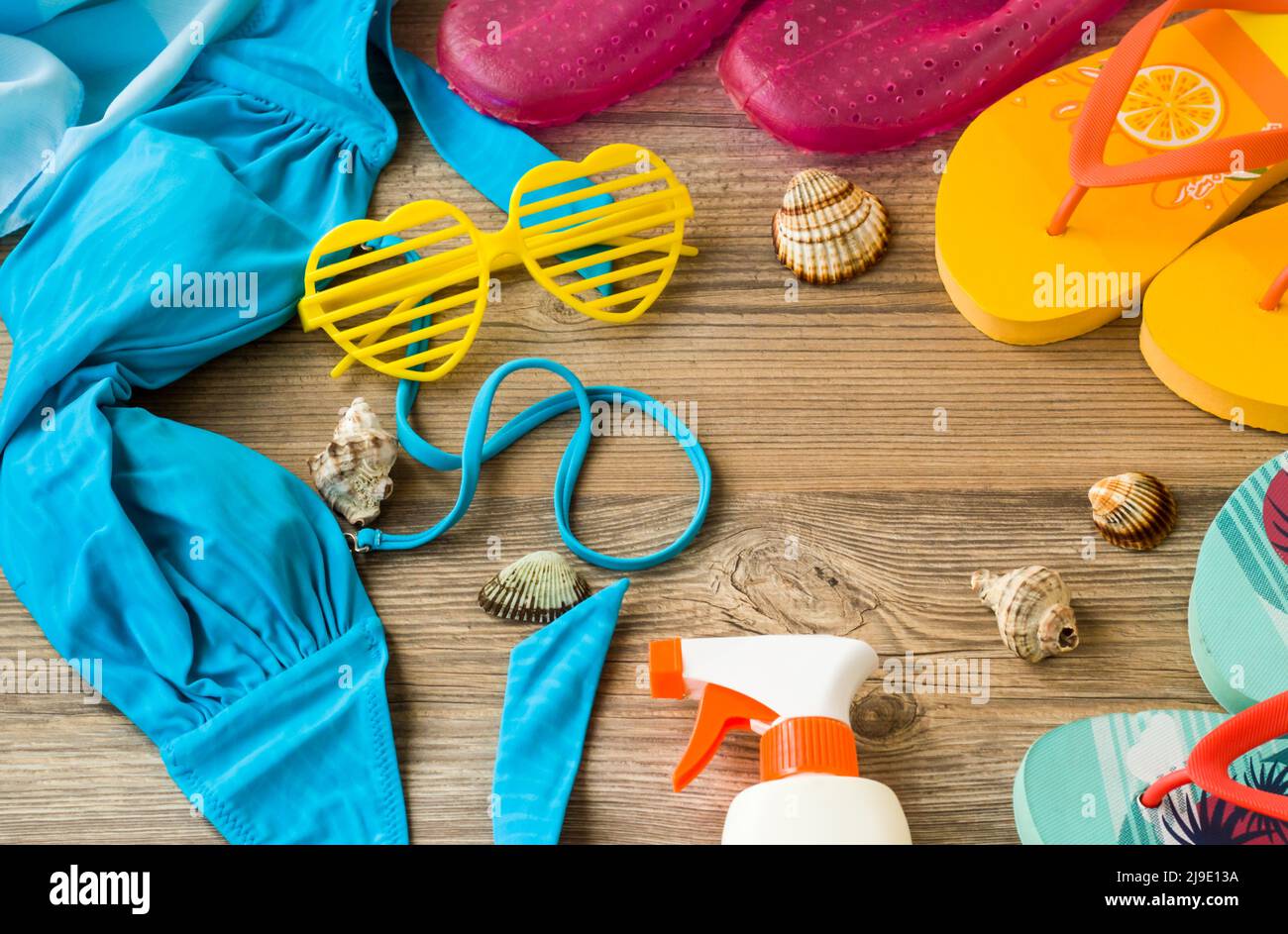 Blue bikini, plastic glasses, suntan oil and beach slippers are ...