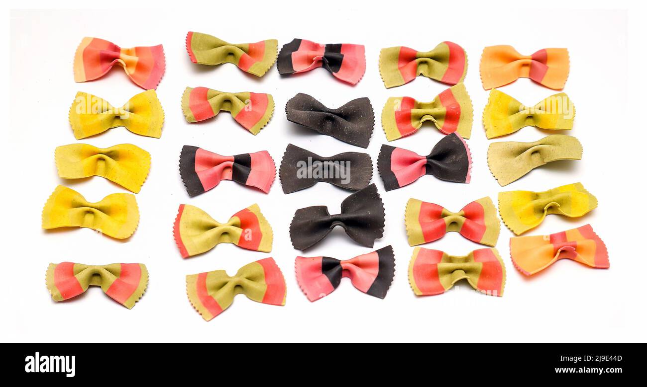 Raw colorful decorative wheat pasta in bow shape on white background ...