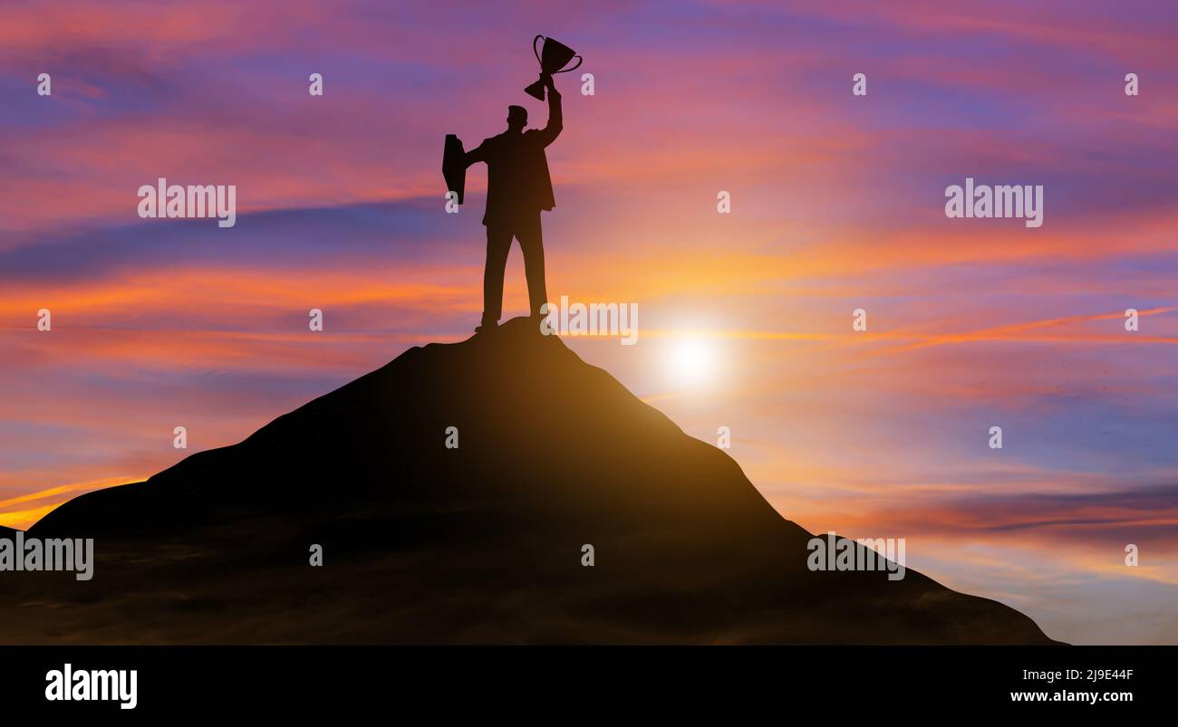 Silhouette victory businessman with trophy climbed to the top of ...