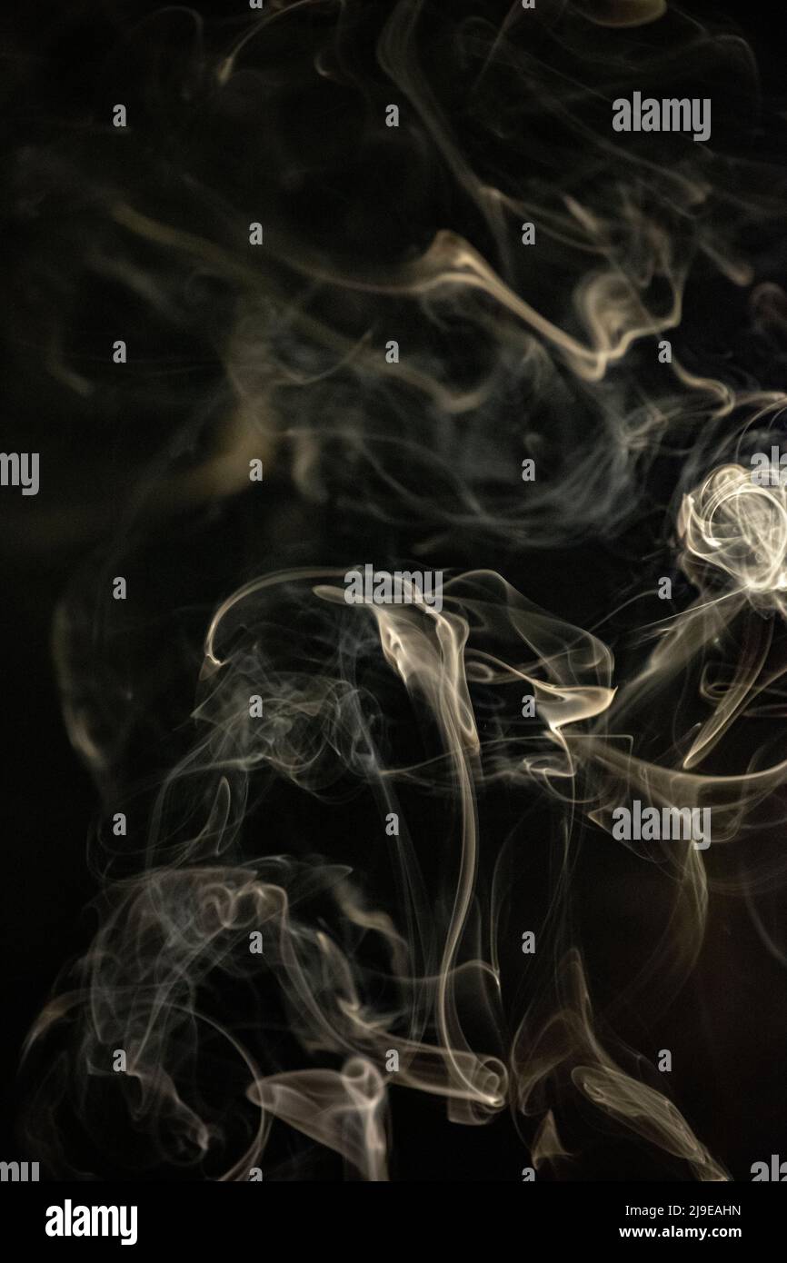 A swirling, ascending smoke pattern with a yellowish gold color on a ...