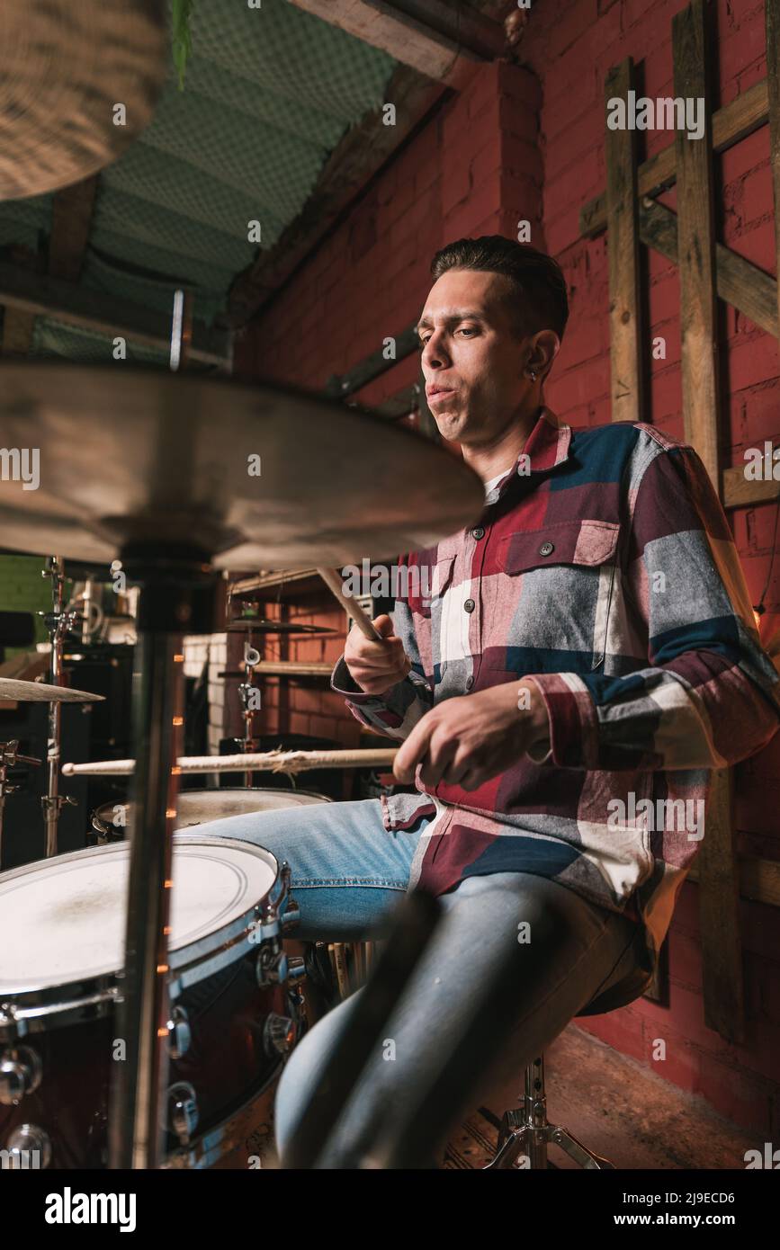 Serious adult male musician in casual wear playing drums on stage ...