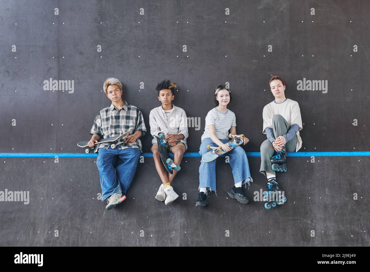 Minimal wide angle shot of diverse group of teenagers sitting on ramp ...