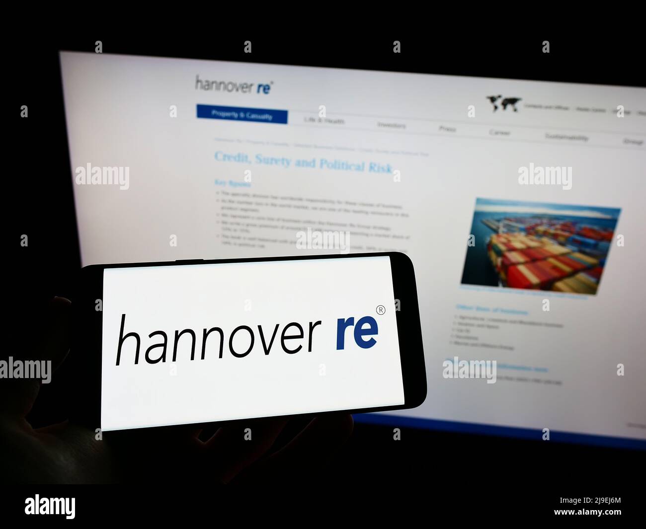 Person holding mobile phone with logo of German reinsurance company ...