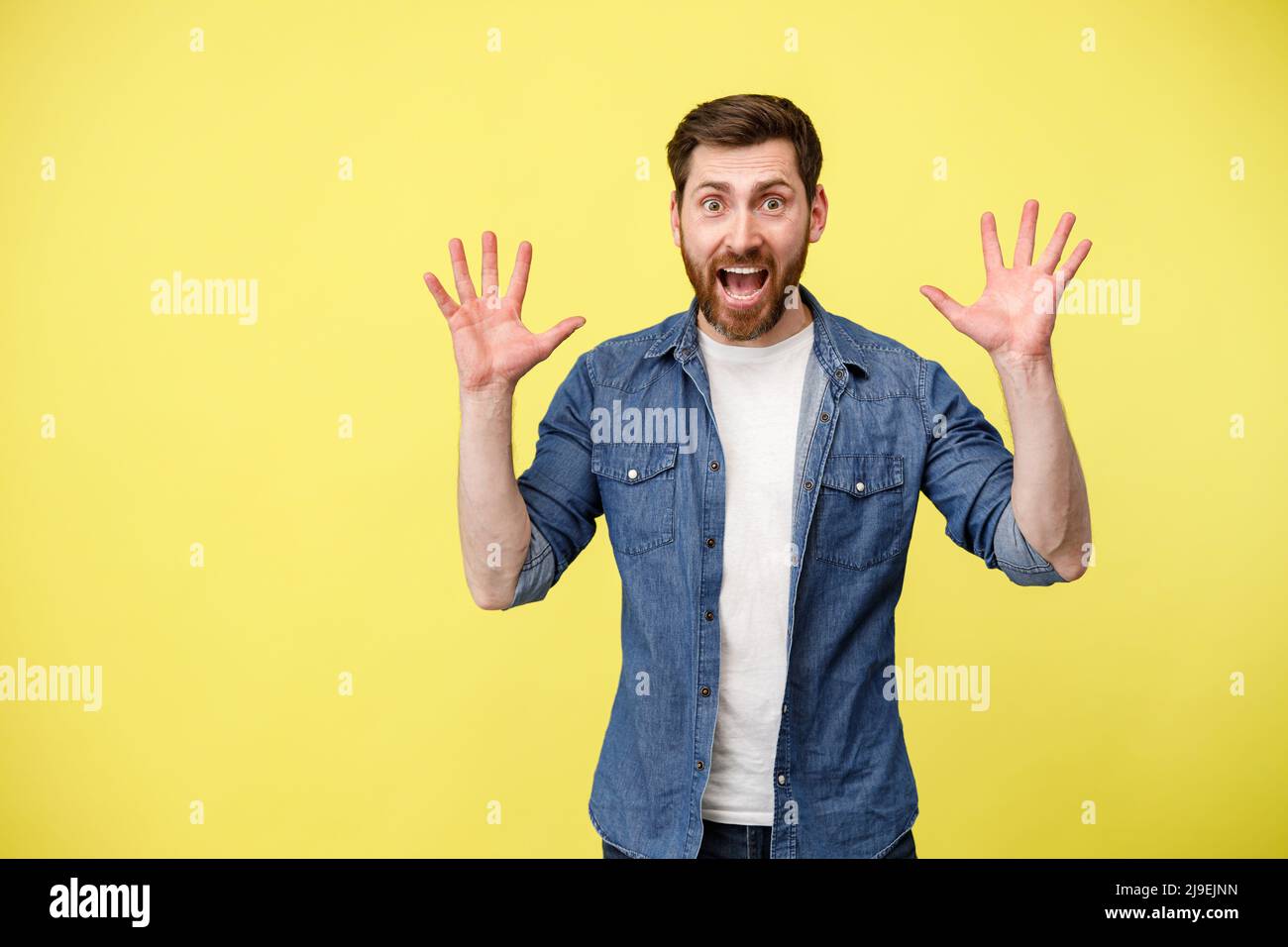 Scared man with raised his hands up and shouting sees something in ...