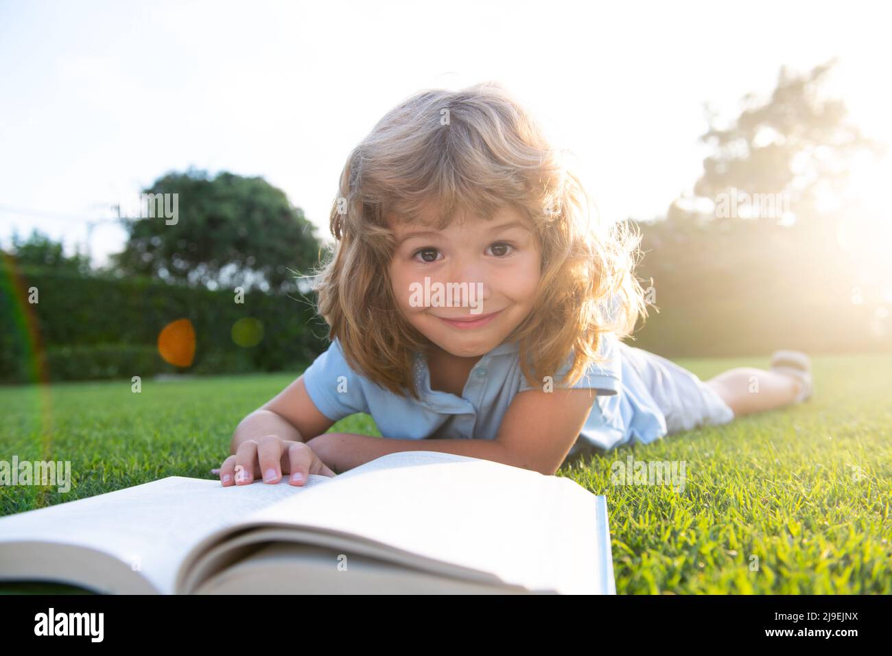 Smart clever boy reading book on green grass Stock Photo - Alamy