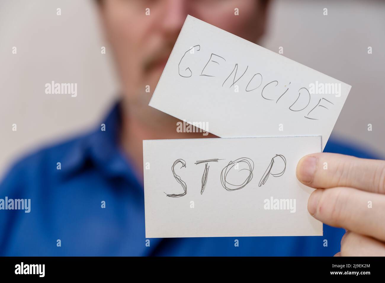 Stop War. The writing is in jagged gray letters on the paper. Man holds ...