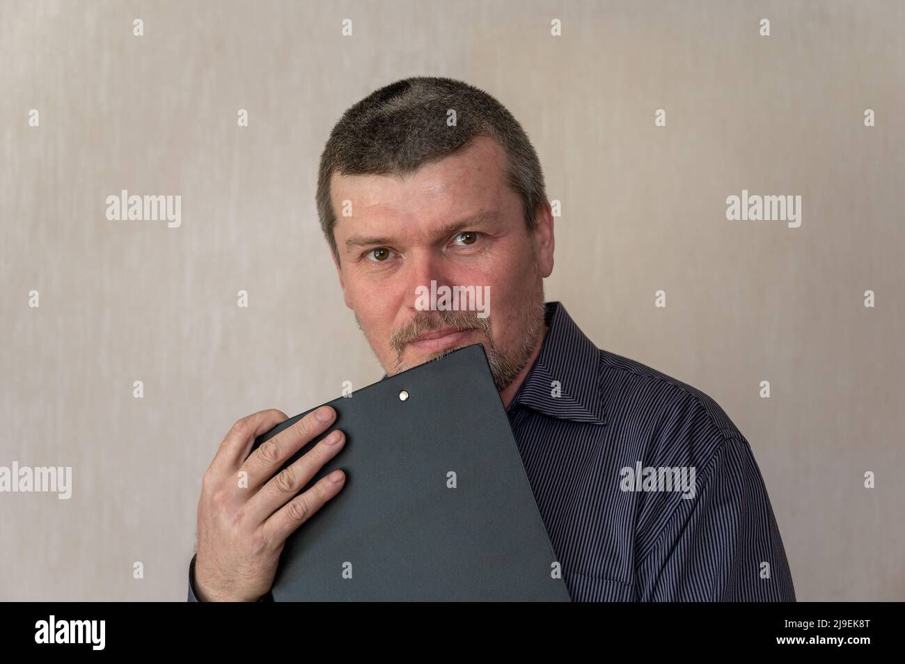 Portrait of a grown man holding a clipboard in front of his chest. Man ...