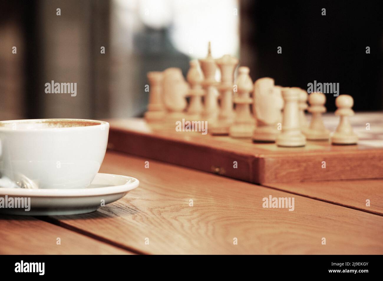 cup of coffee near chess on a wooden table, playing chess over a cup of ...