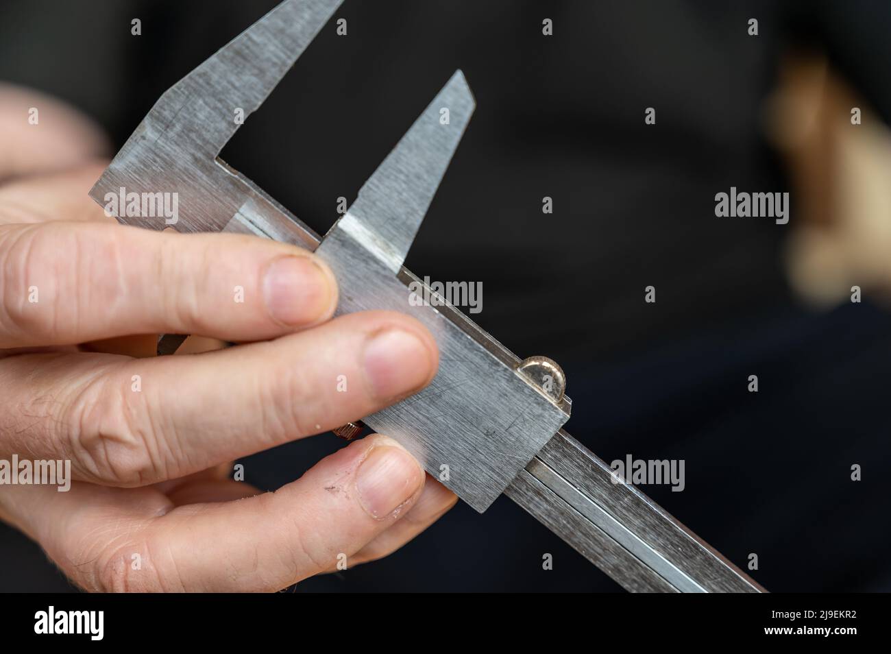 A man's hand holding a caliper. An adult man with a high-precision ...