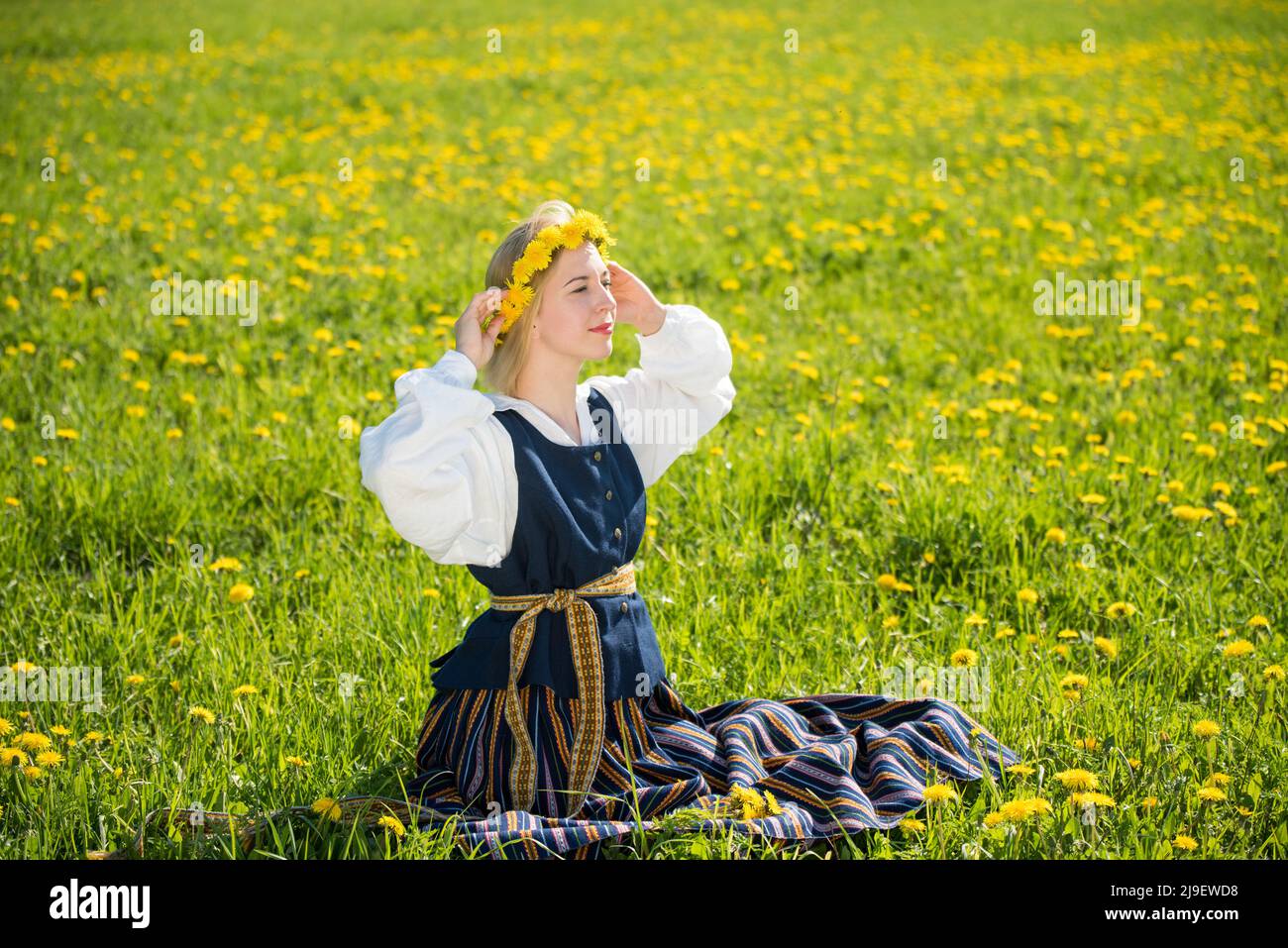 Young woman in national clothes wearing yellow dandelion wreath in ...