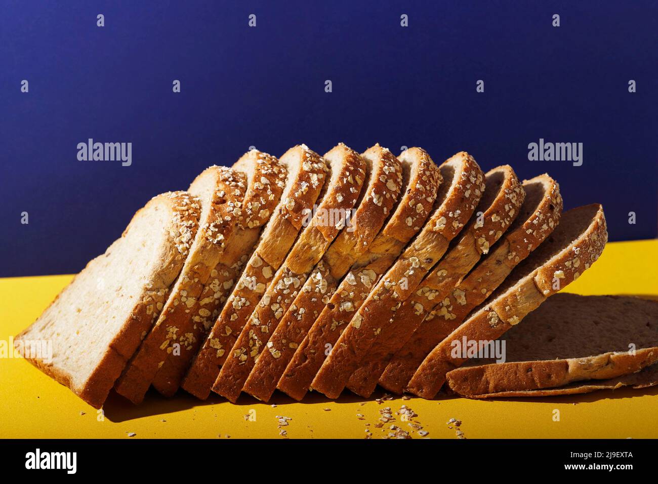 Close Up Whole Grain Bread with Oat Flakes and Seeds on Blue and Yellow ...