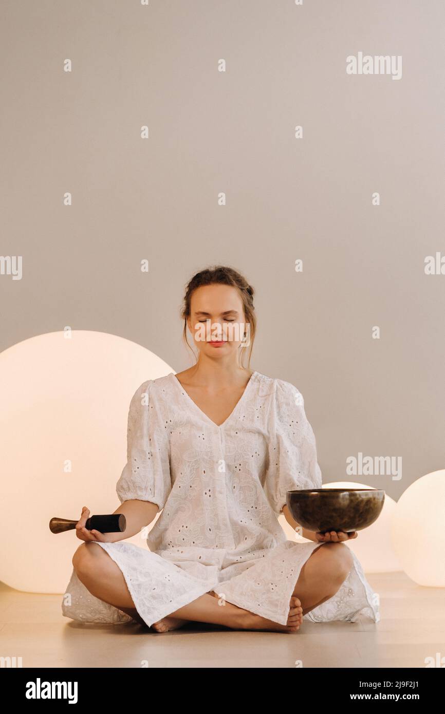 Portrait of a female yoga teacher playing a Tibetan bowl or singing a ...