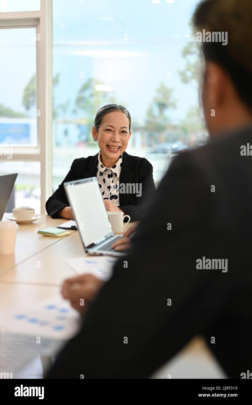 Positive Asian aged female boss or executive manager talking with male ...