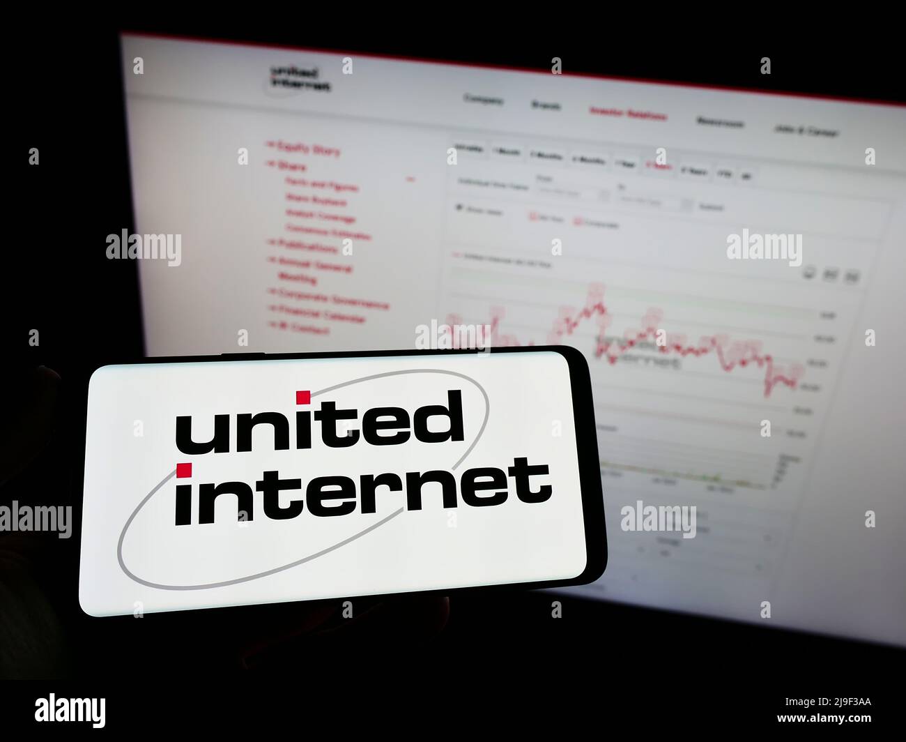 Person holding mobile phone with logo of German company United Internet ...