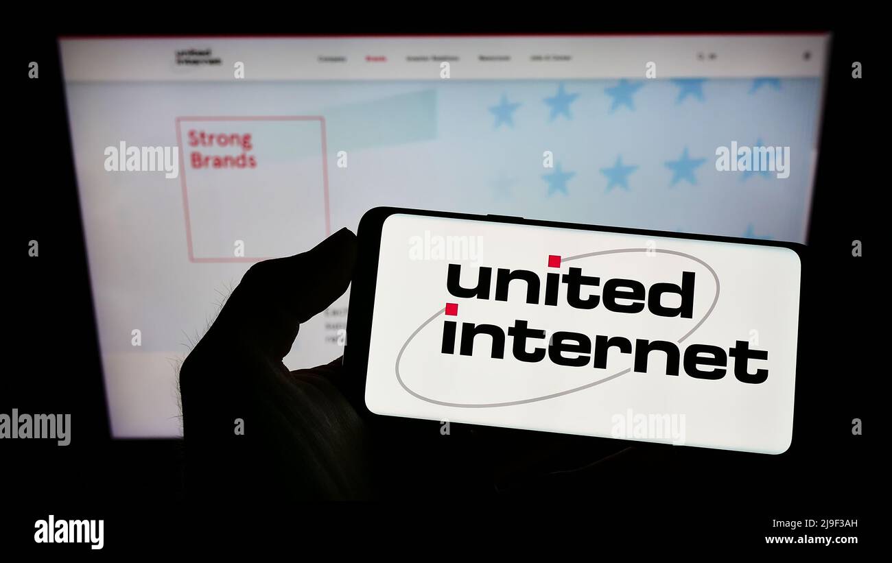 Person holding smartphone with logo of German company United Internet ...