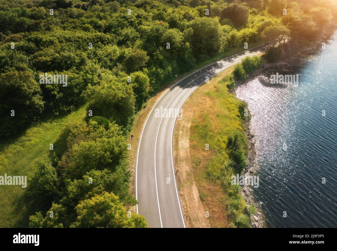 Aerial view of road near blue sea, forest at sunset in summer Stock ...