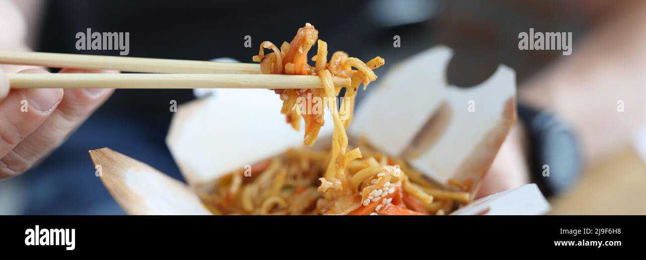 Man eating chinese food with wooden chopsticks Stock Photo - Alamy