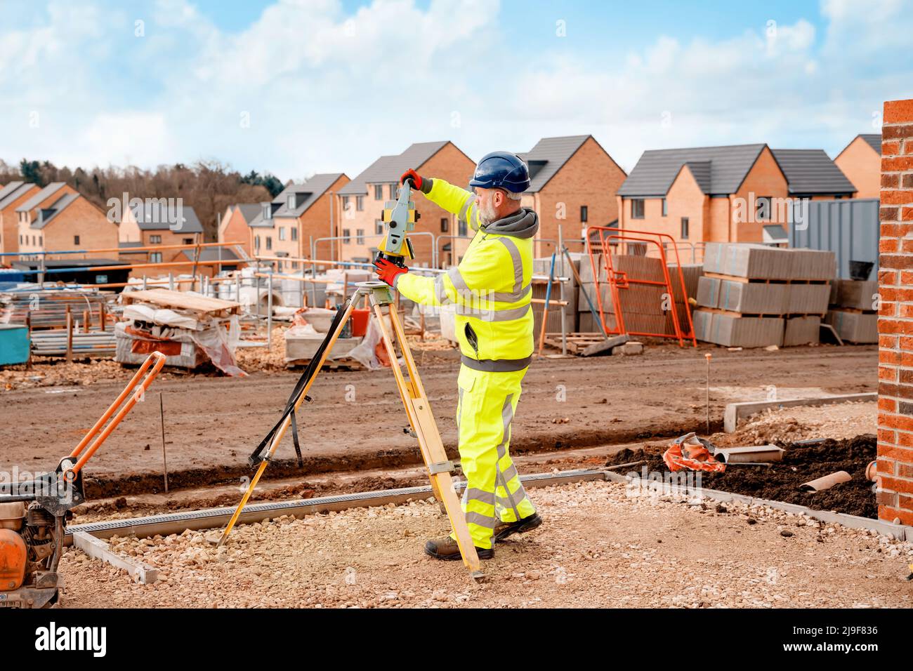 Site engineer in hi-viz installing surveying instrument on construction ...