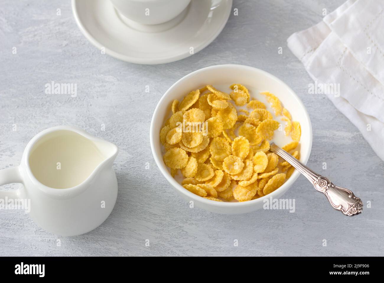 Sweet crunchy cornflakes with milk on a gray textured background. Fast ...