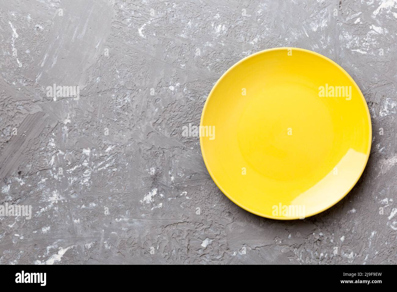 Top view of empty yellow plate on cement background. Empty space for ...