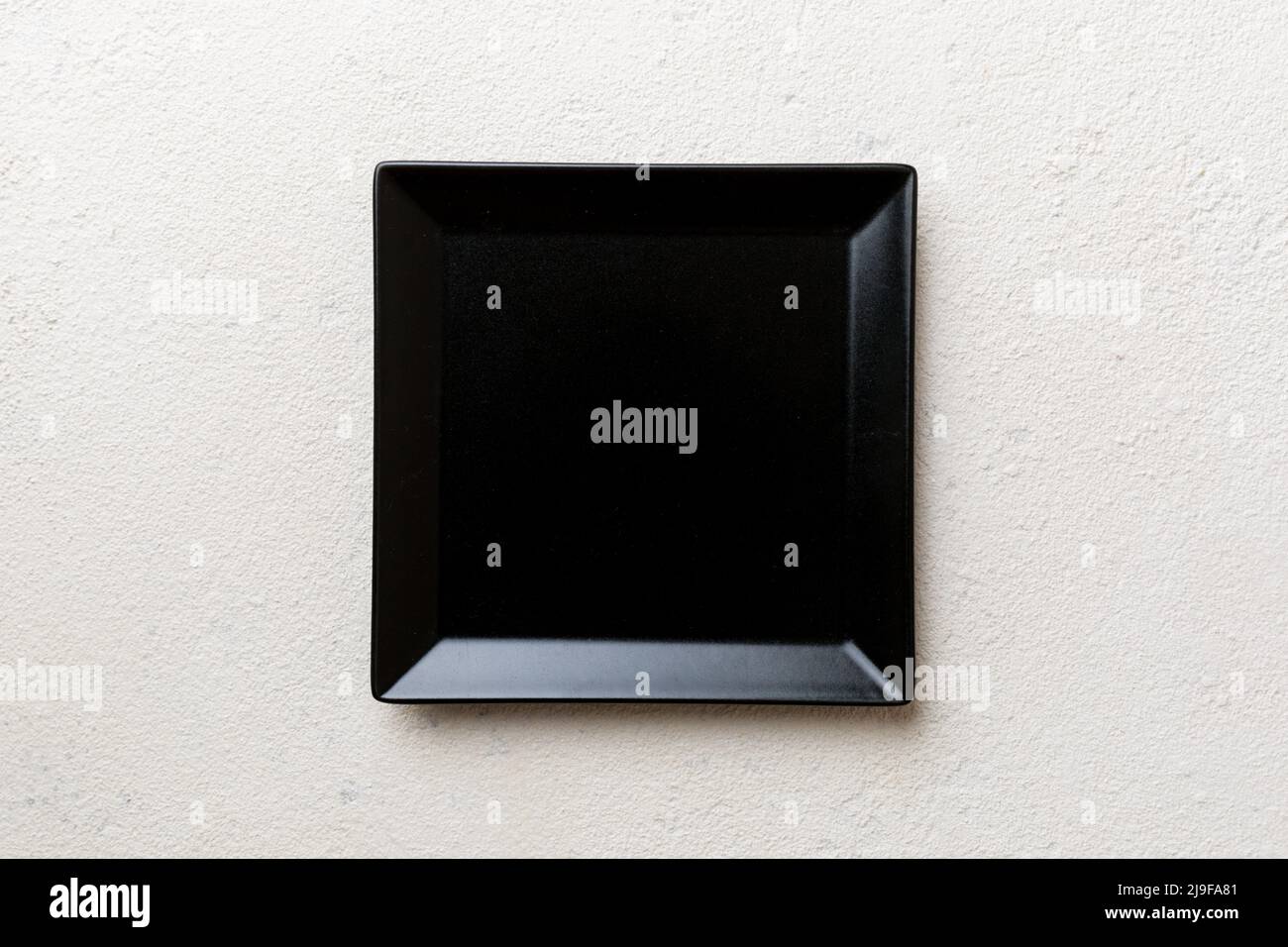 Top view of empty square plate on cement background. Empty space for ...