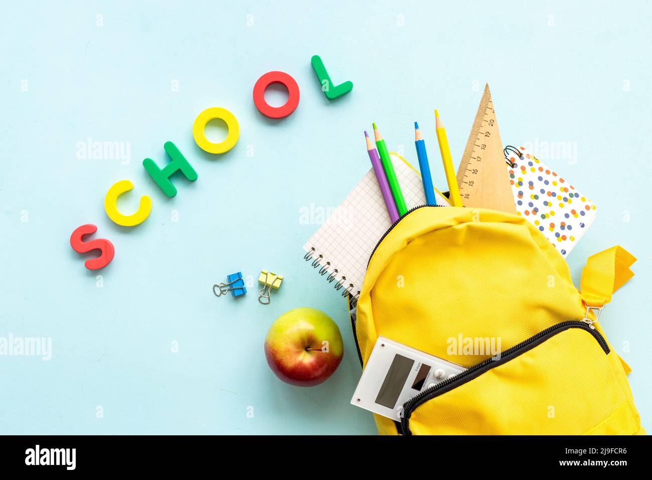 Layout of yellow school backpack full of stationery with apple Stock ...