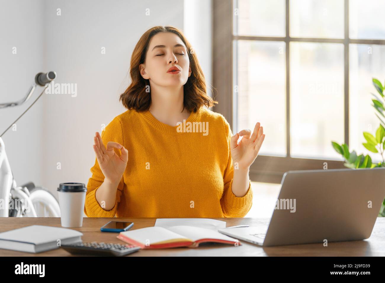 Woman working in the office and practicing deep breathing for calm and ...