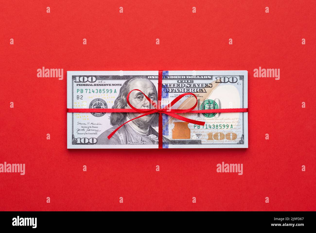 Dollar bills tied with a red ribbon on red background. Financial bonus ...