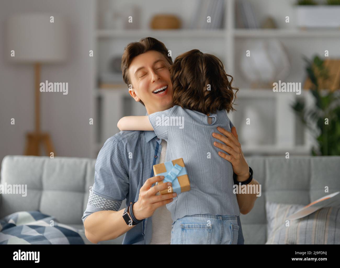 Child daughter is congratulating her father and giving him a present ...