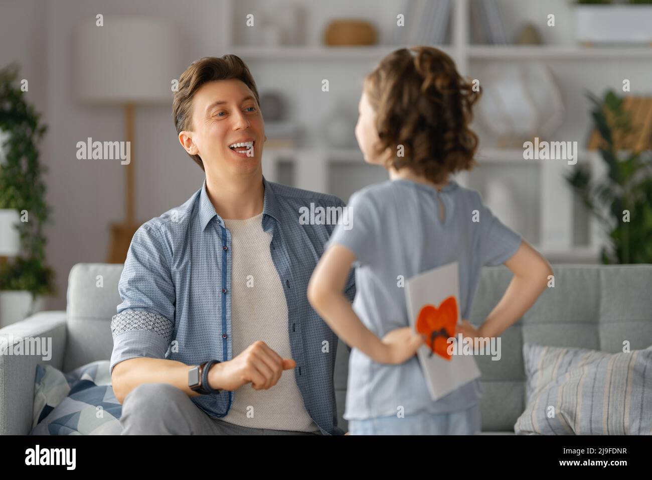 Child daughter is congratulating her father and giving him postcard ...
