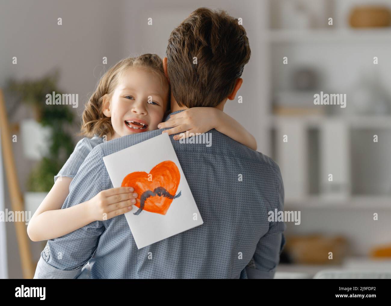 Child daughter is congratulating her father and giving him postcard ...