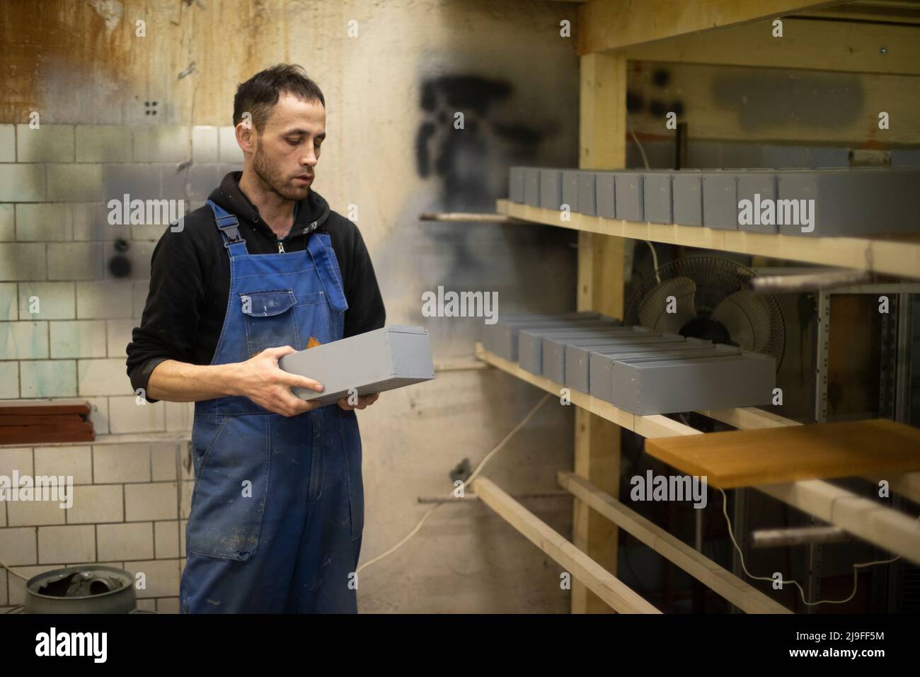 Worker puts box on shelf. Man folds painted boards. Guy works in wood ...