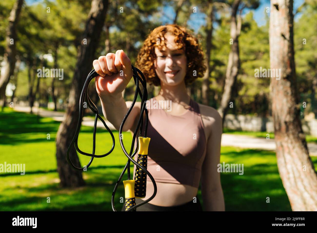 Portrait of a fit redhead lady holding her skipping rope in front of ...