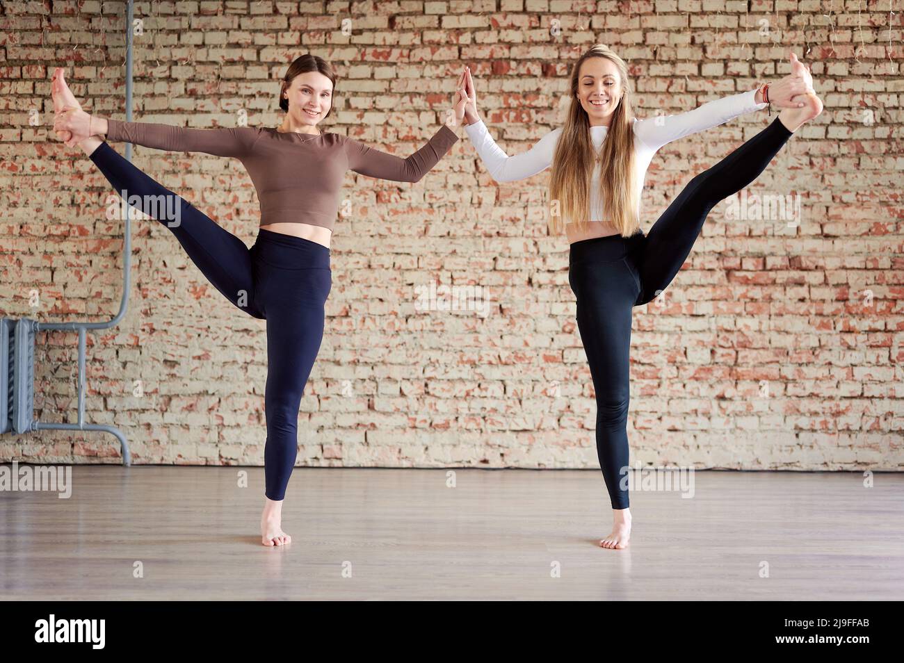 Young attractive females stretching legs in yoga studio relaxation ...