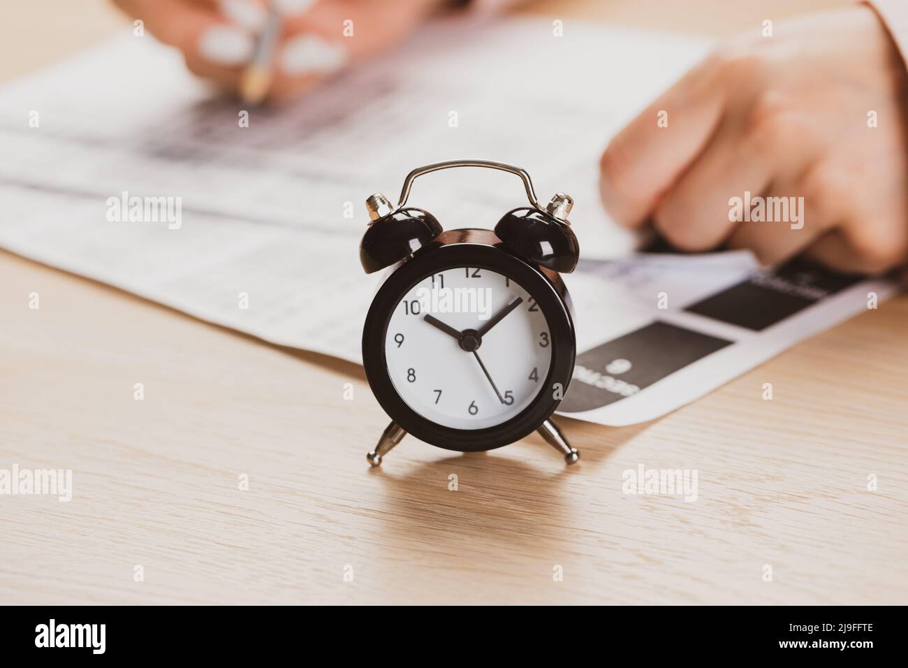 alarm clock with time running out. Students hands to take exams, write ...