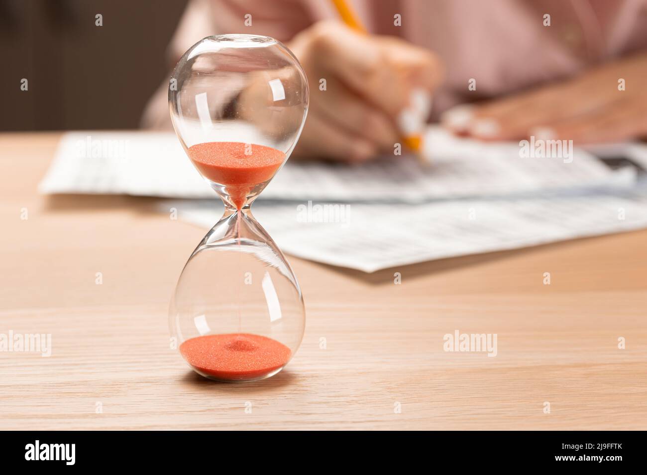 Hourglass with time running out and student hand testing in exercise ...