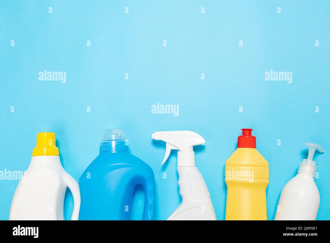 House cleaning supplies on blue background. Row of plastic bottles with ...
