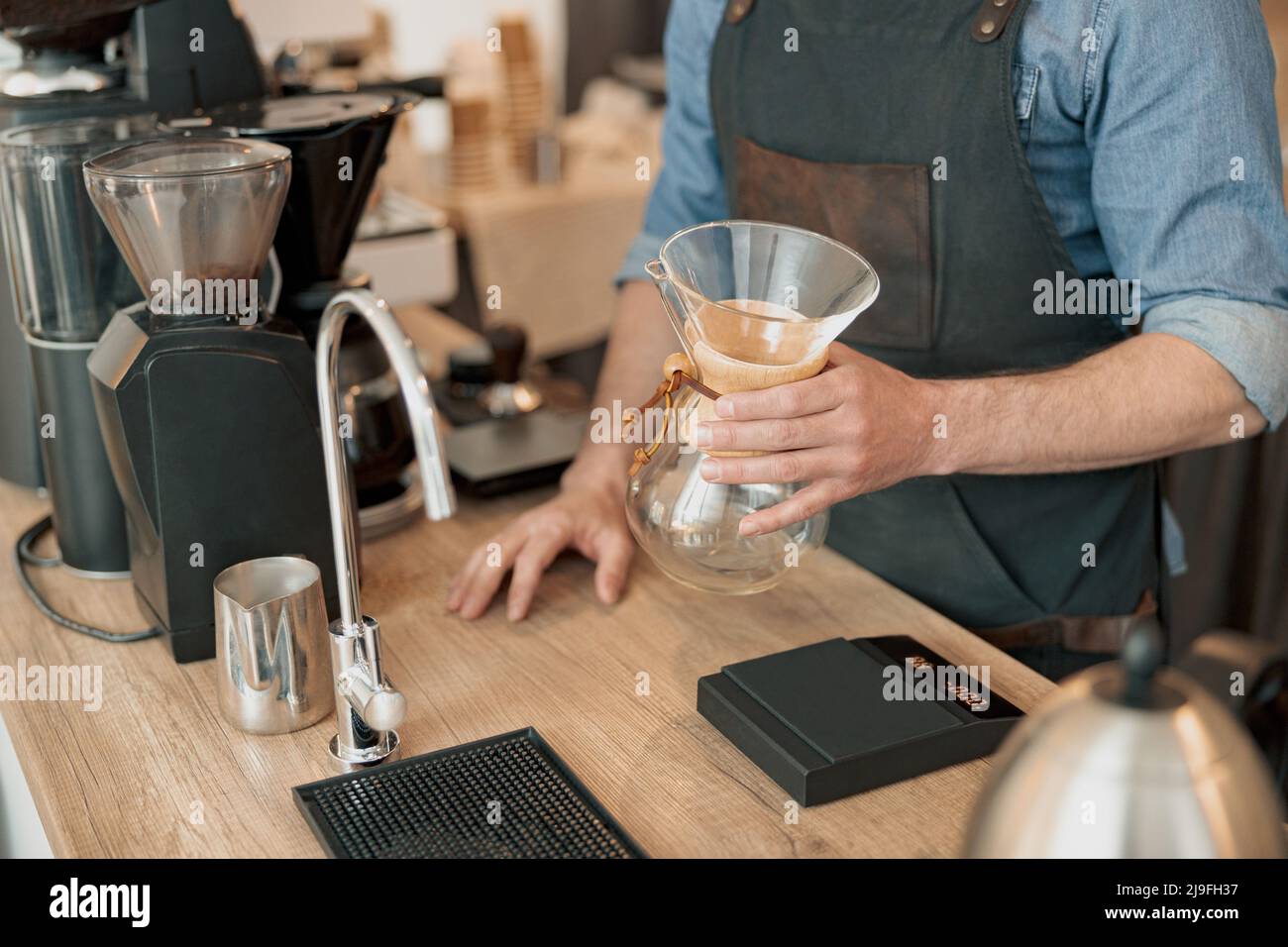 barista holds in his hands a glass vessel for making filter coffee ...