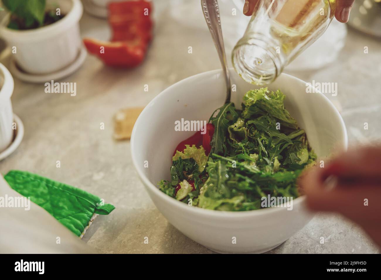 Closeup of process of adding olive oil to green salad Stock Photo - Alamy