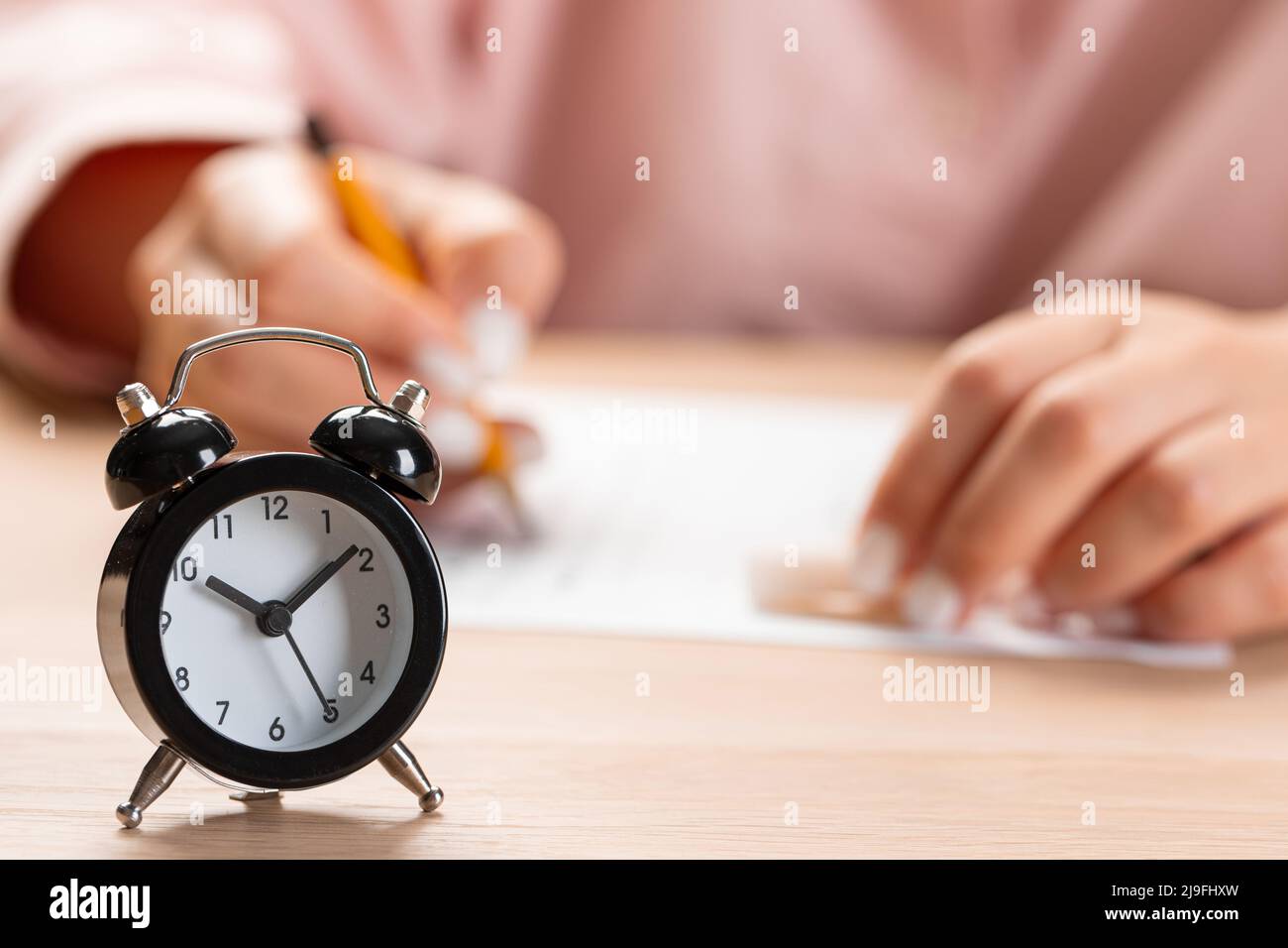 alarm clock with time running out. Students hands to take exams, write ...