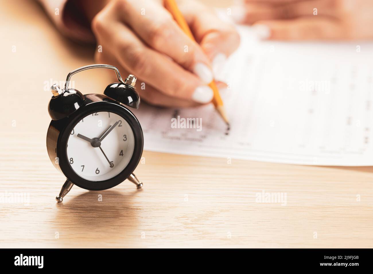 alarm clock with time running out. Students hands to take exams, write ...